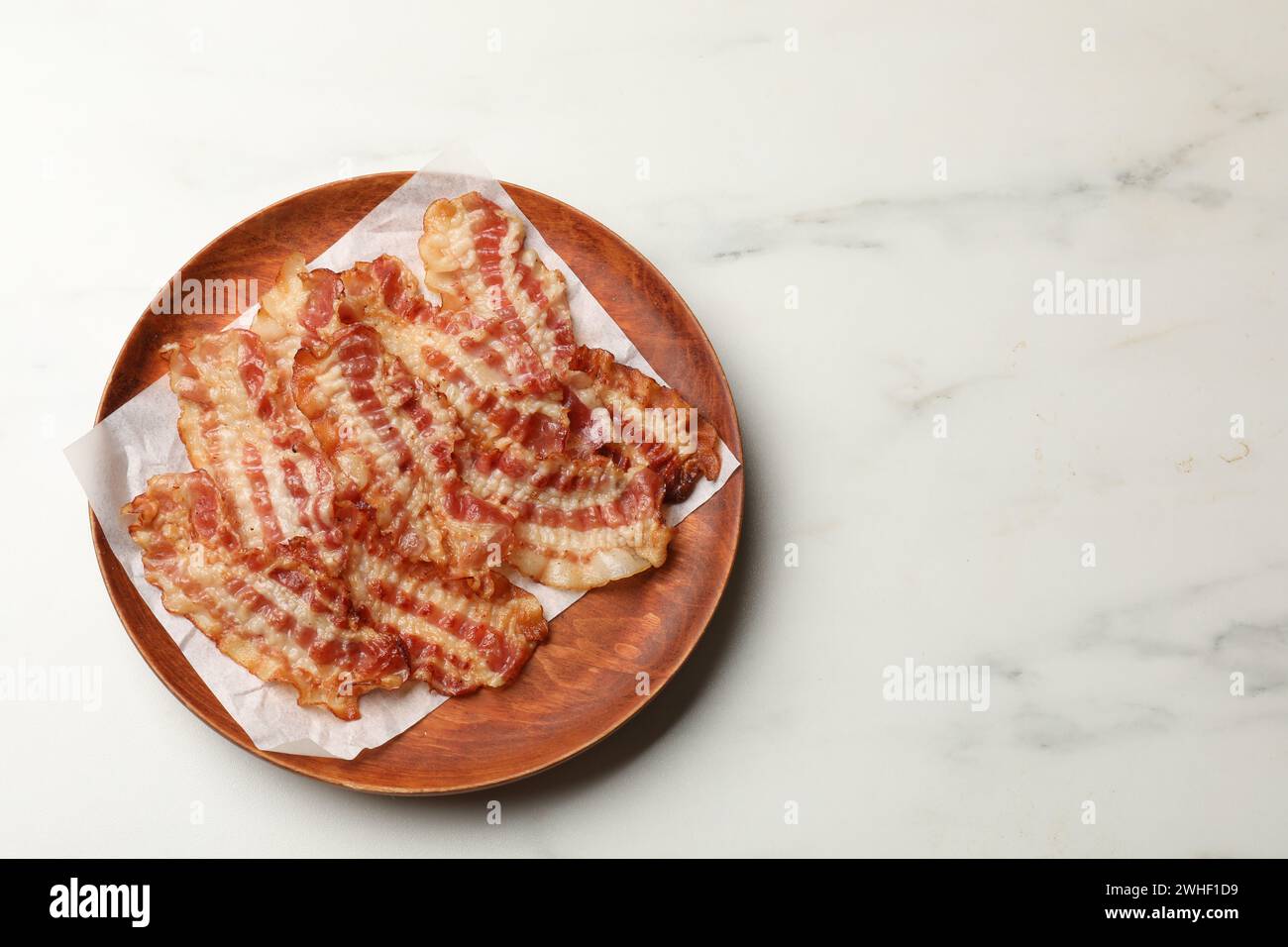 Delicious fried bacon slices on white marble table, top view. Space for ...