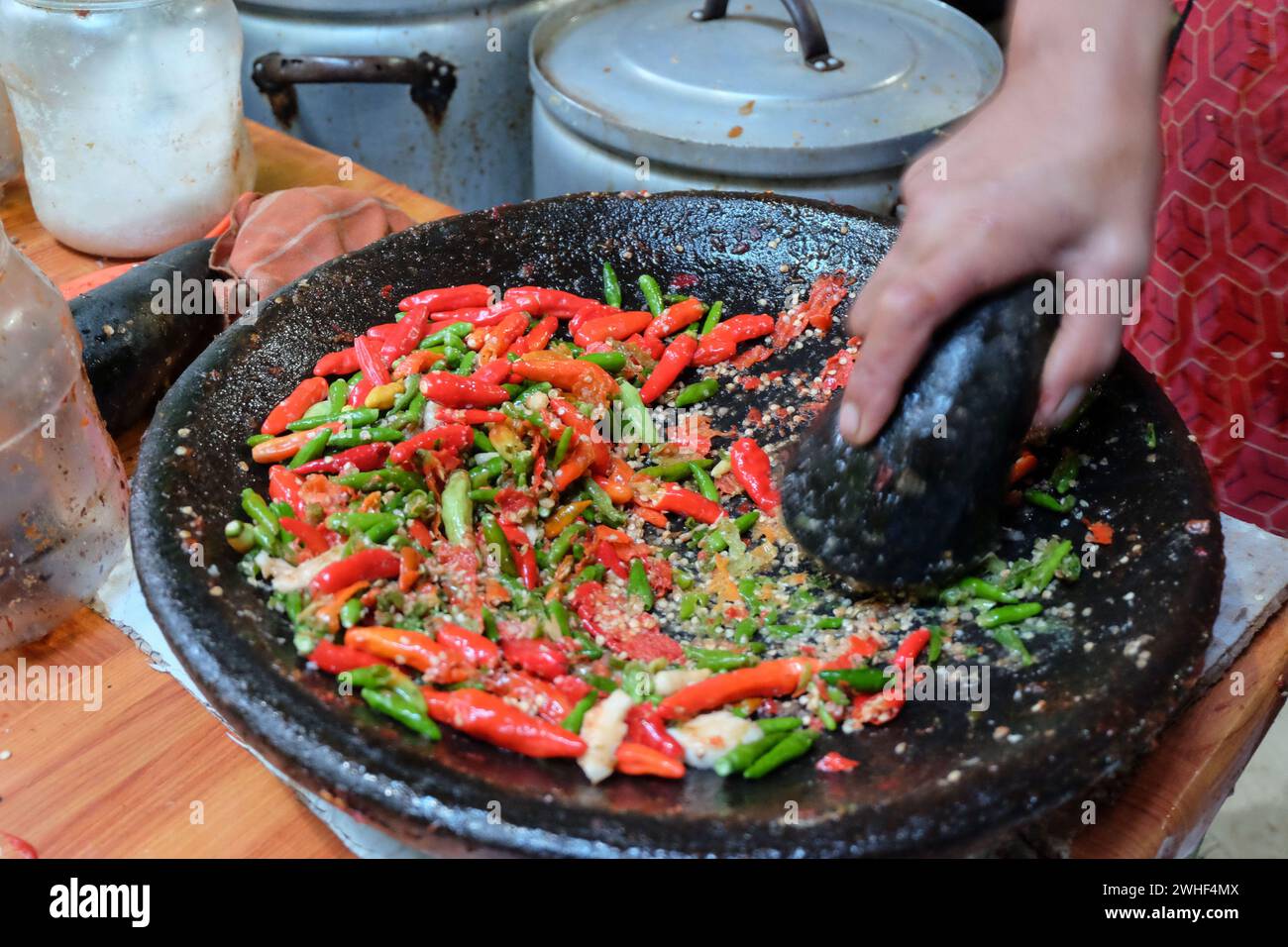 Female Hand Grinding red and Green Chilli on Stone Mortar making Sambal ...
