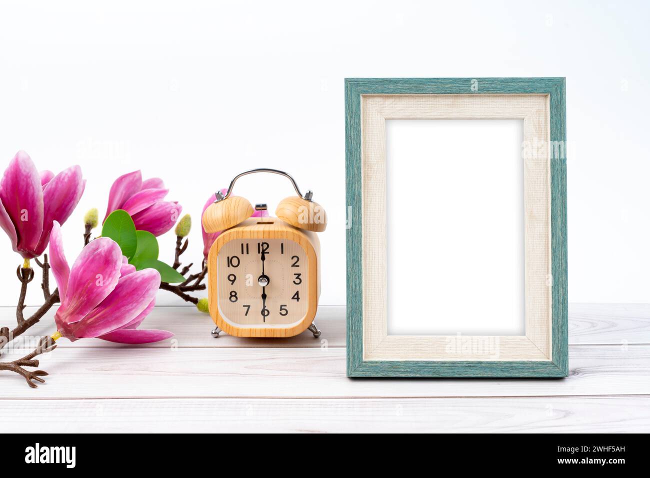 Blank picture frame and alarm clock on wooden floor with copy space and ...