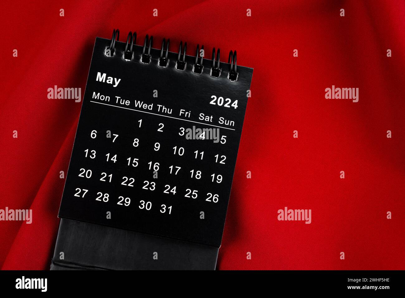May 2024 Black spiral desktop calendar on red textile background Stock ...