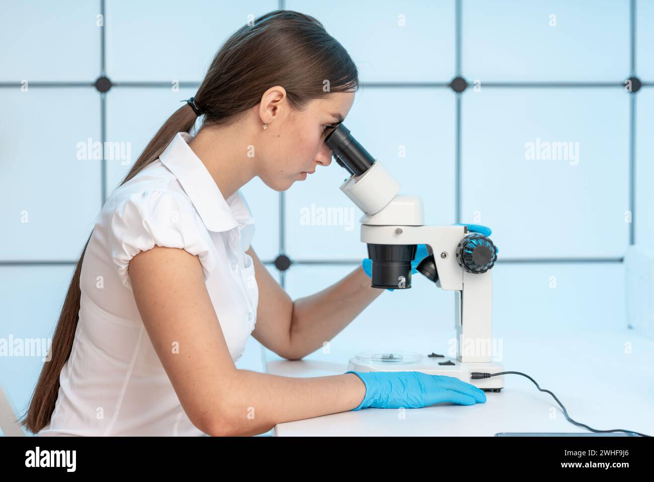 Woman looking through microscope Stock Photo - Alamy