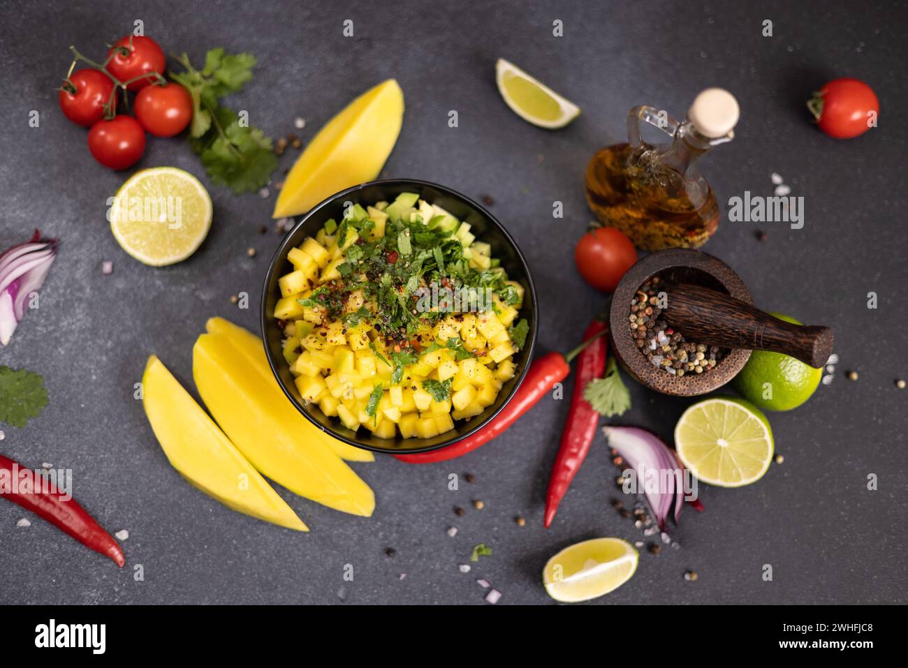 Cooking mango salsa - sliced chopped ingredients in a black ceramic ...
