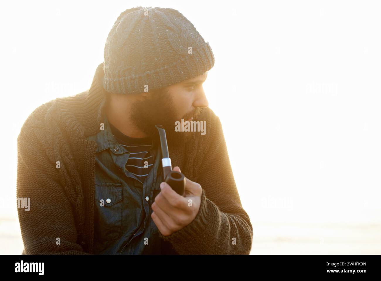 Holiday, man and smoking a pipe on beach, thinking and sunrise with ...