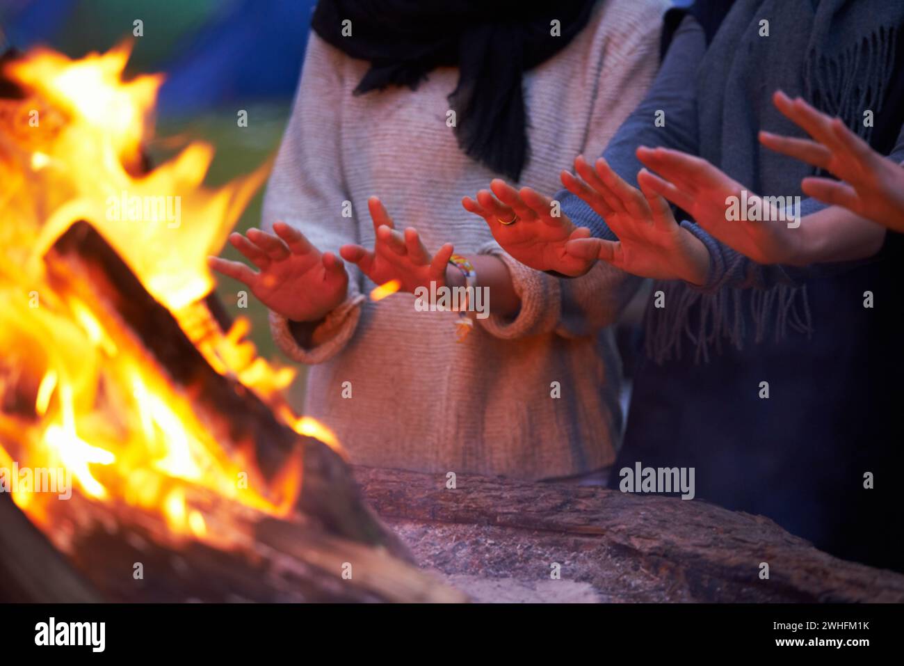 Hands, fire and people camping outdoor, keeping warm with open flame at ...