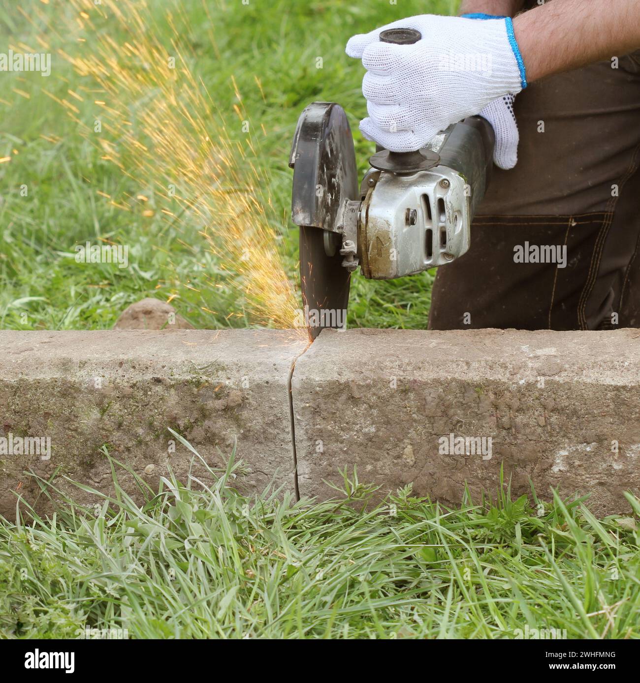Construction worker cutting concrete plate for fence foundation using a ...