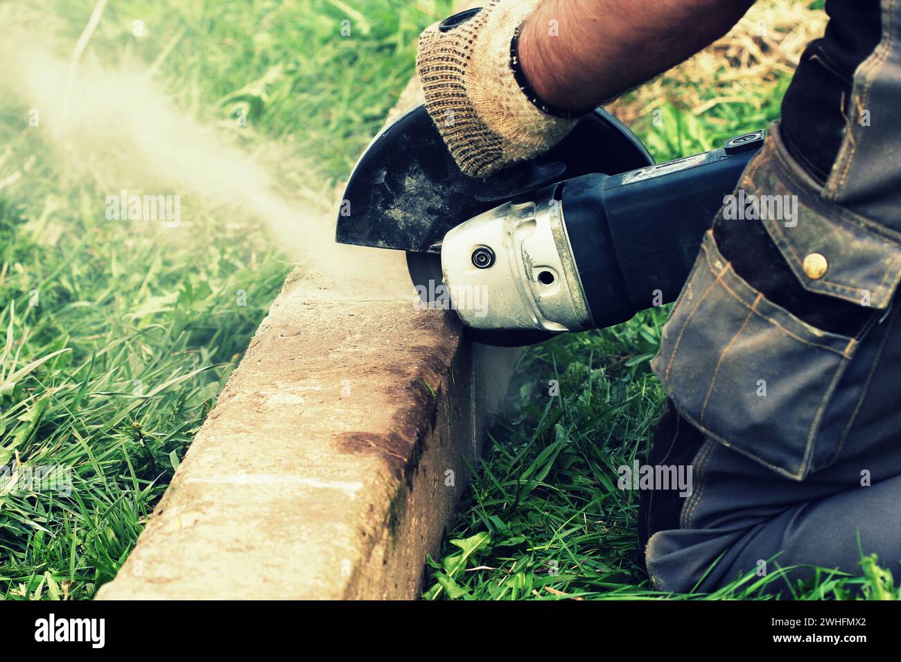 Construction worker cutting concrete plate for fence foundation using a ...