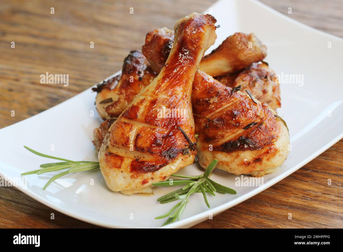 Grilled chicken legs with rosemary served on white plate. Dinner ...