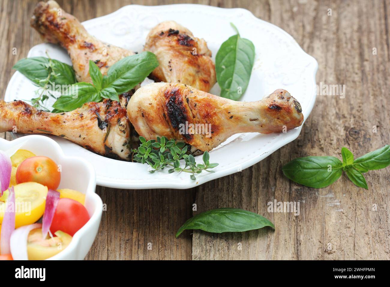 Grilled chicken legs with rosemary served on white plate. Dinner ...