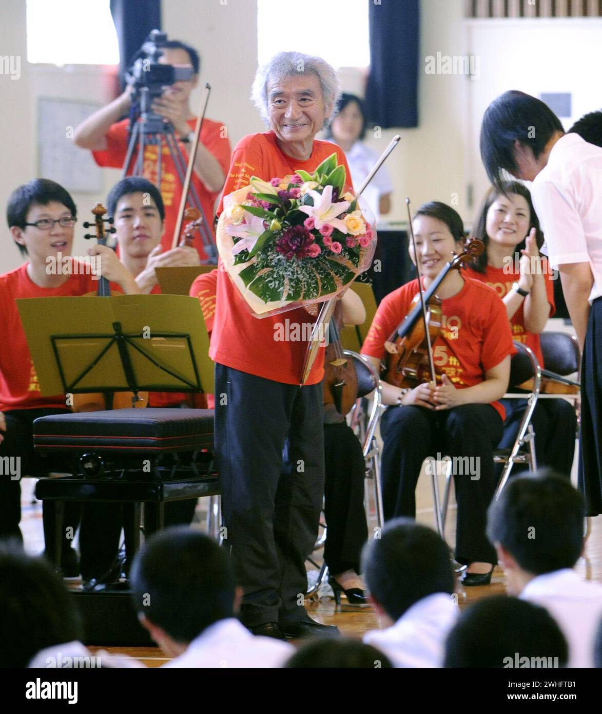 Japanese conductor Seiji Ozawa receives a bouquet from a student after ...