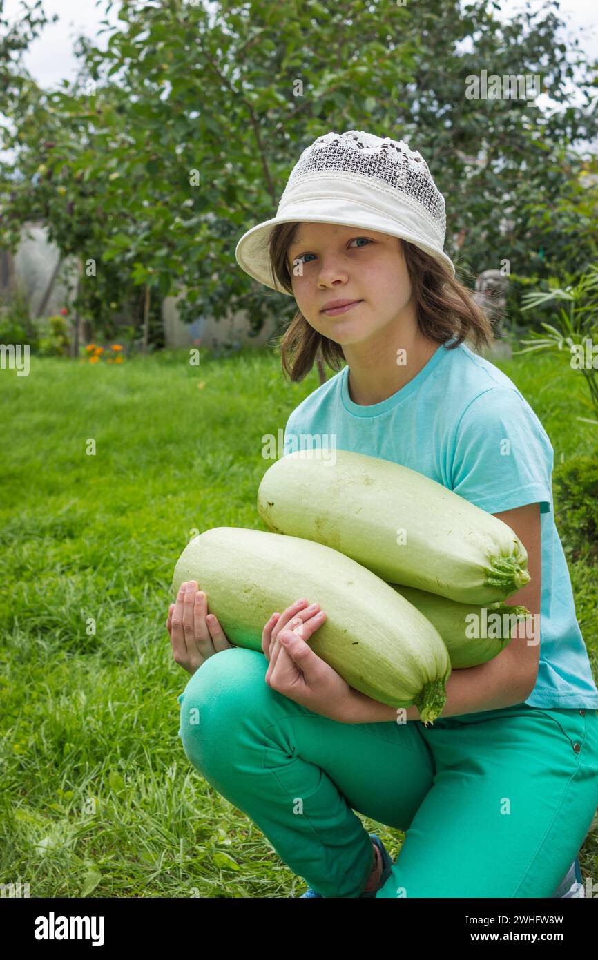 Girlie holds three large vegetable marrows Stock Photo - Alamy