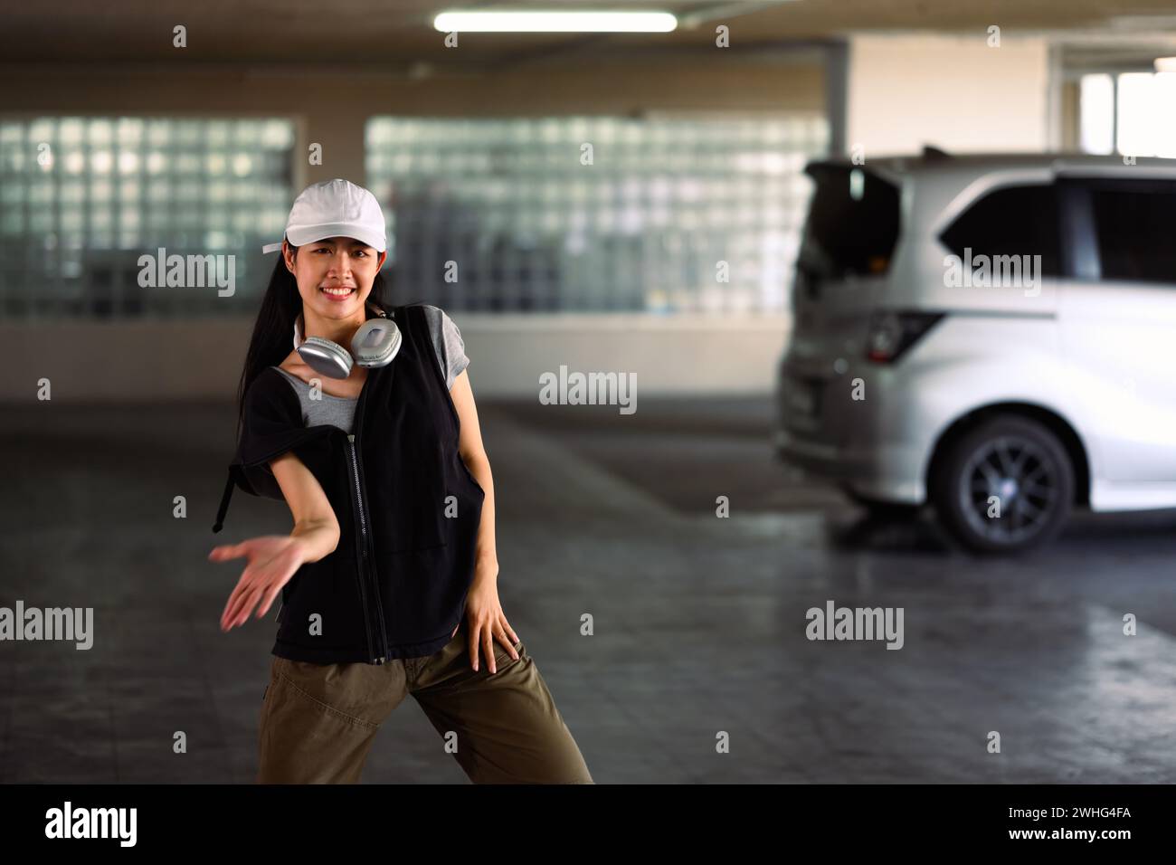 Young beautiful woman dancing in style of hip hop aesthetics in parking ...