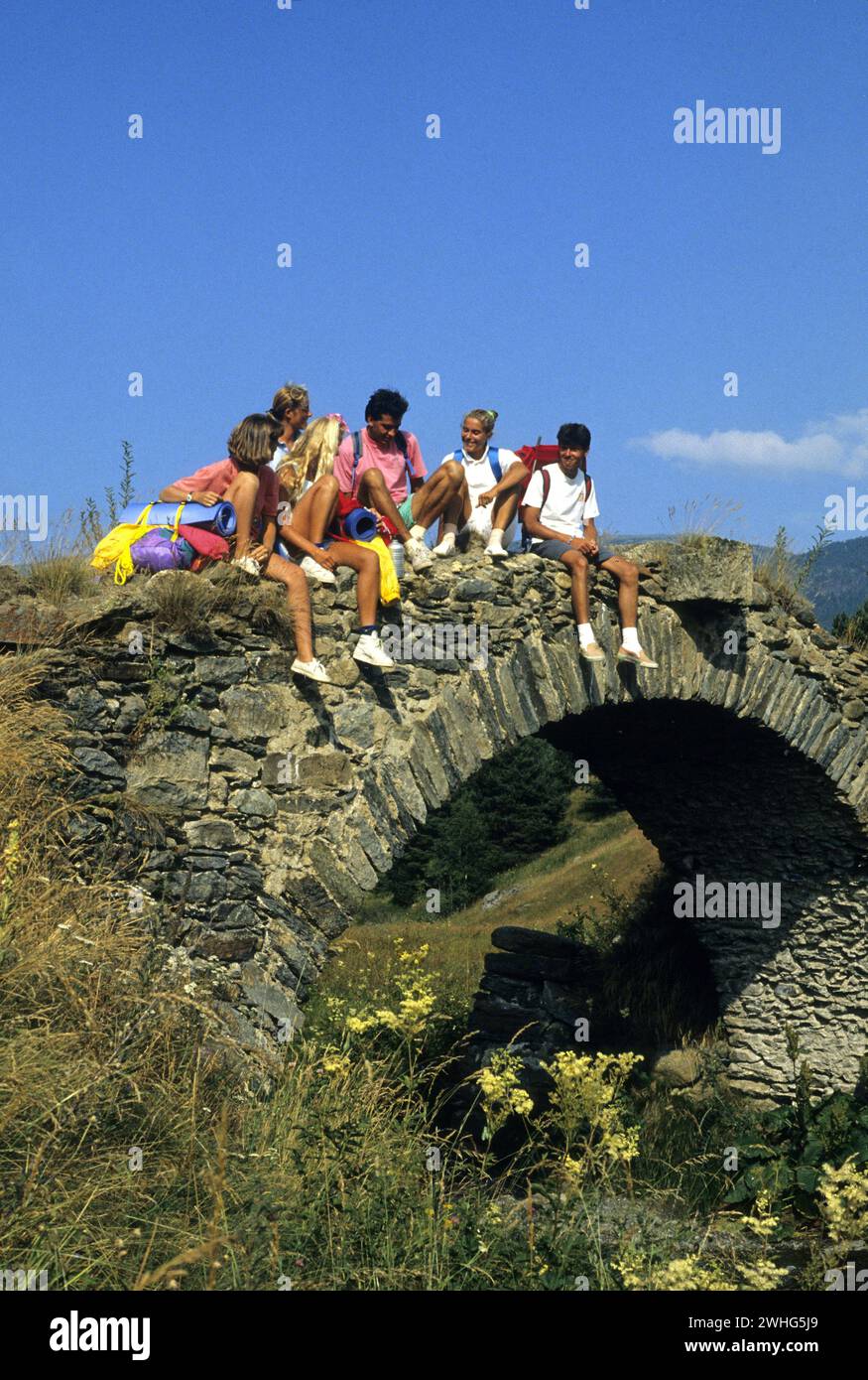 group of teenagers outdoor country balade resting on little rock bridge ...