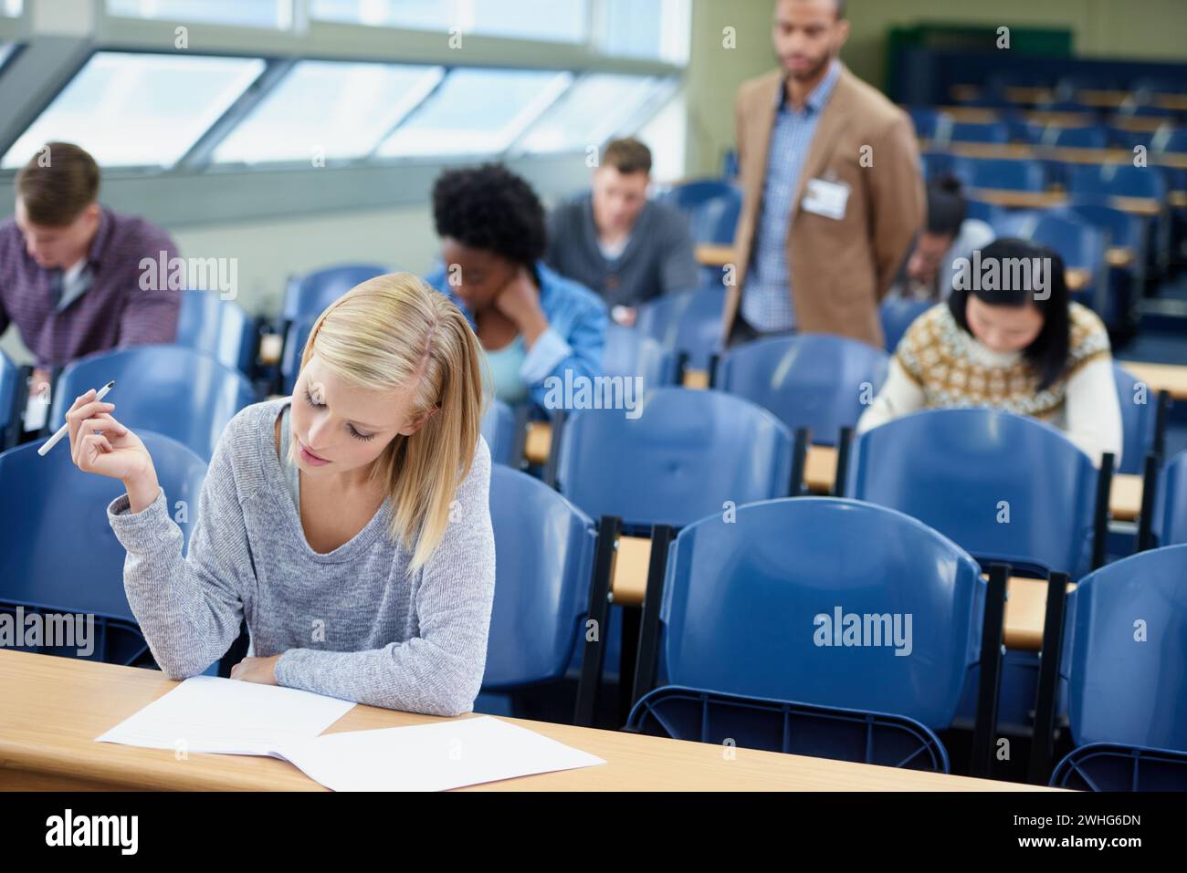 Exam, classroom and student with pen for thinking, assessment and ...