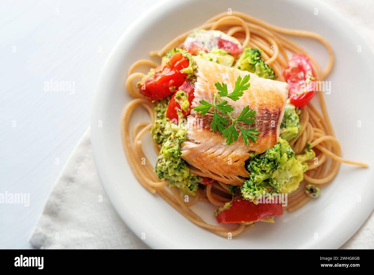 Wild salmon fillet on whole grain spaghetti with broccoli, tomatoes and ...