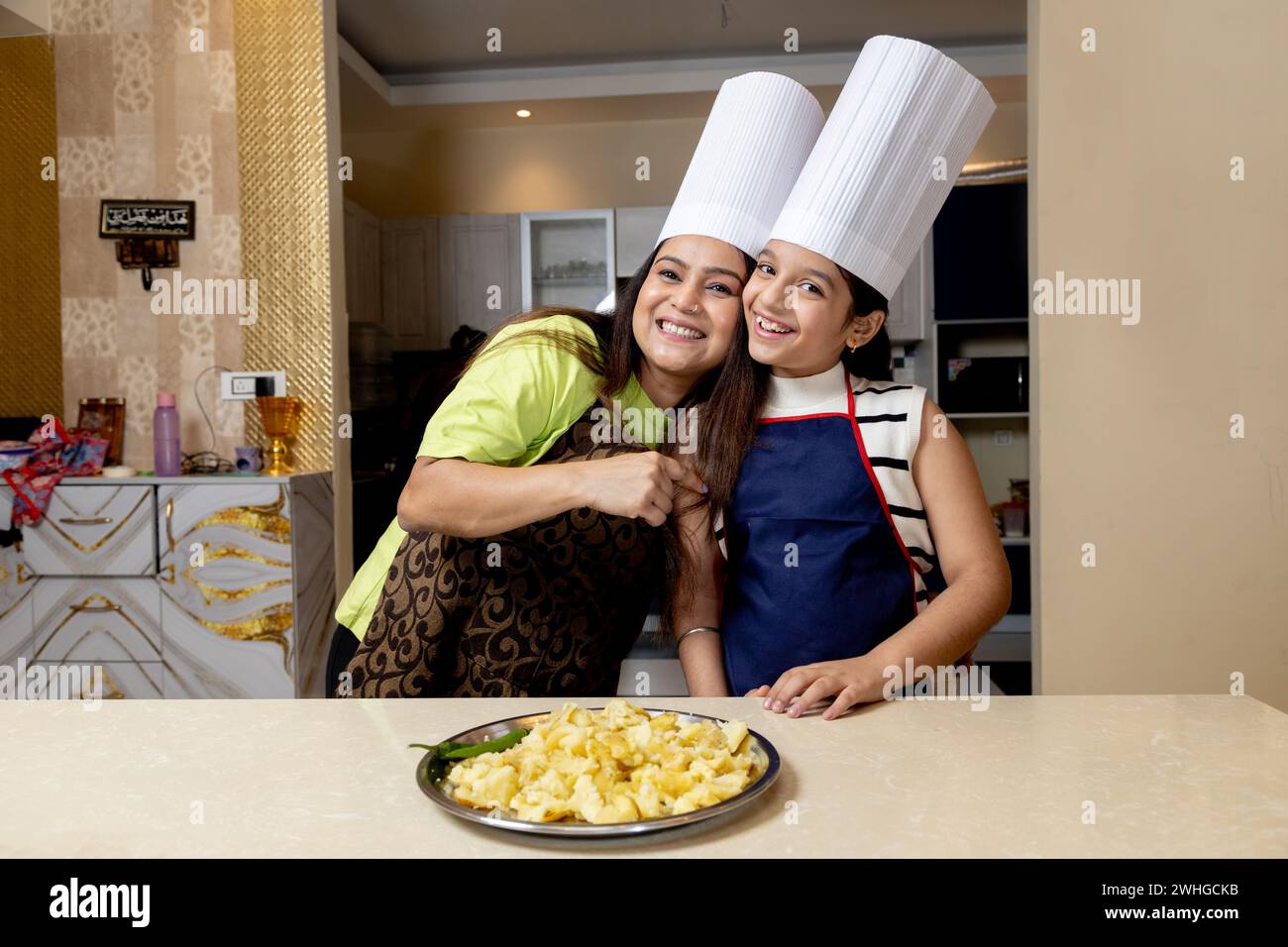 Happy indian mother and daughter dressed in cook uniform wearing a ...