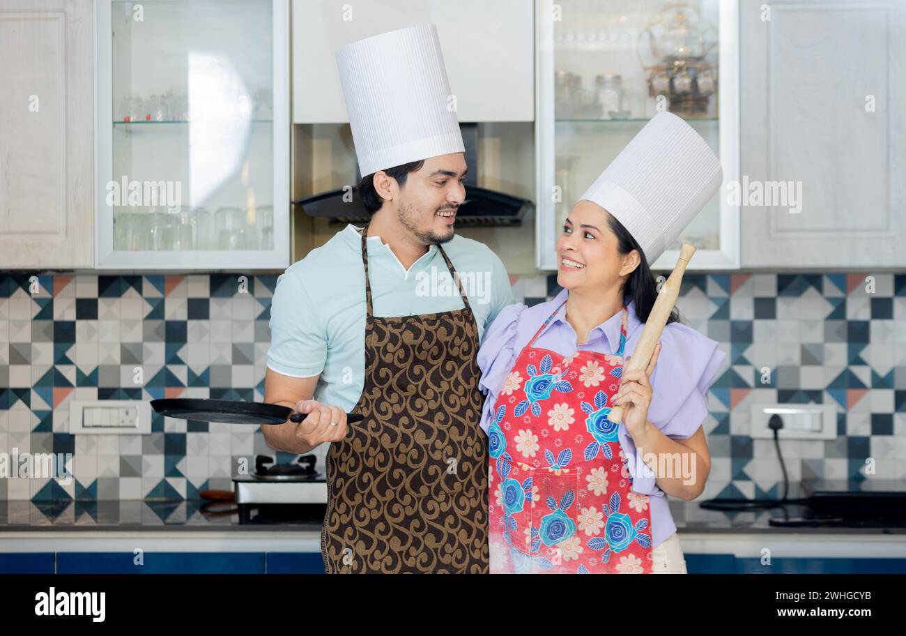 Happy indian couple dressed in cook uniform wearing a apron , chef hat ...