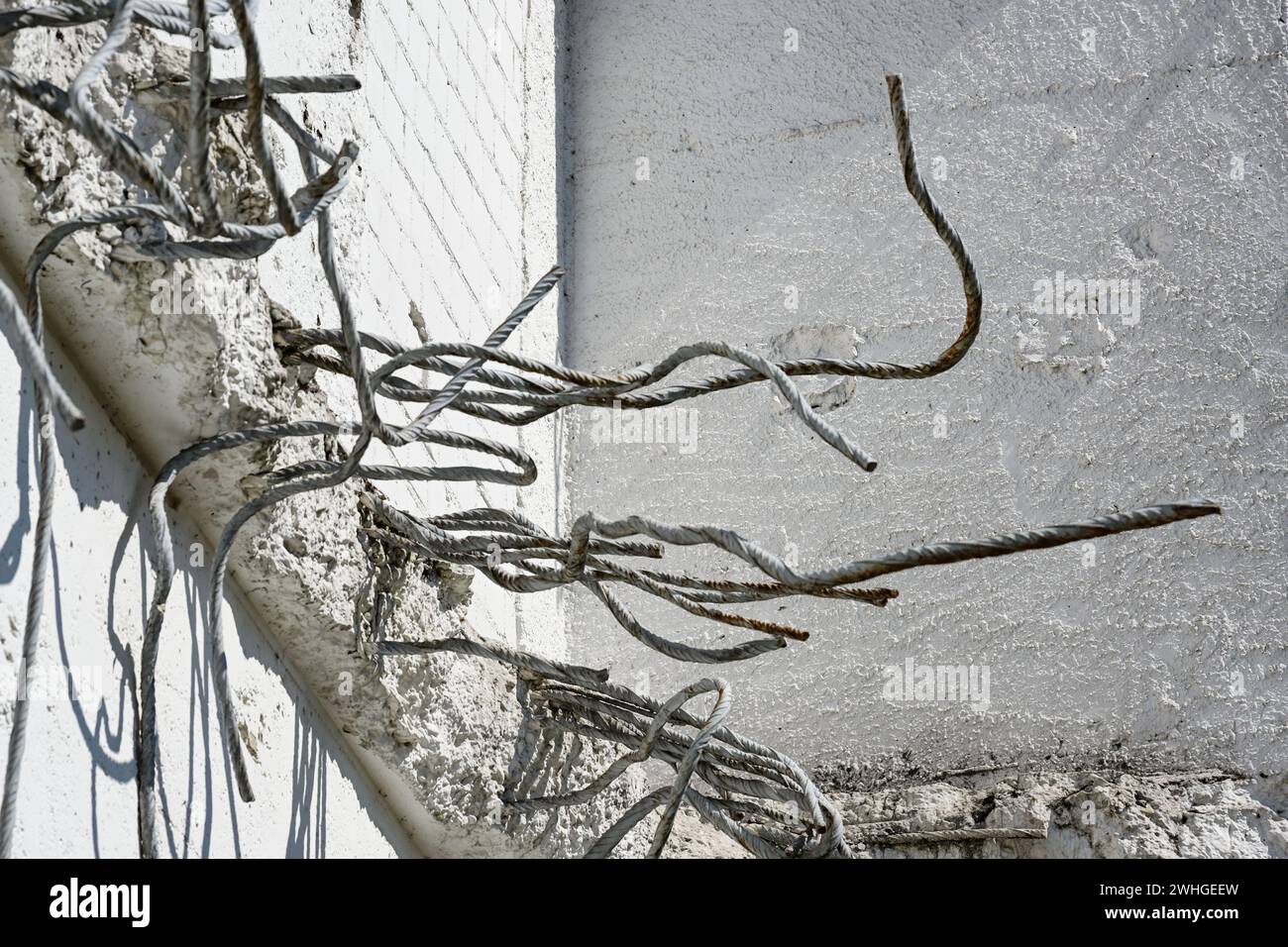 Rebars from iron stick out of a bright concrete wall after demolition ...