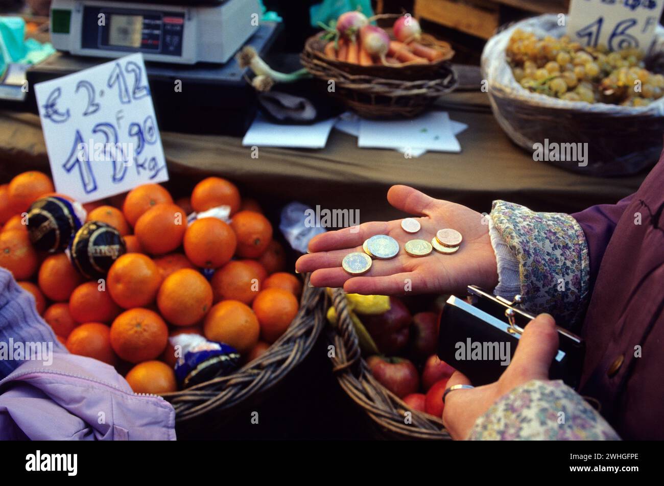 Hand of old woman holding euros coins to buy fruits on market label ...