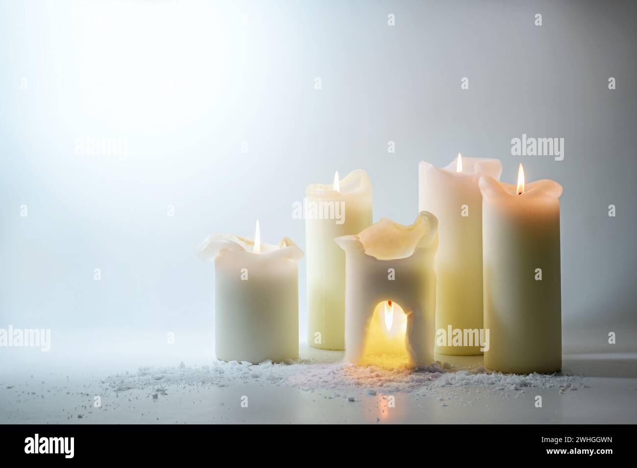 Group of white candles, one is burning overhead in a warm cave, surreal ...