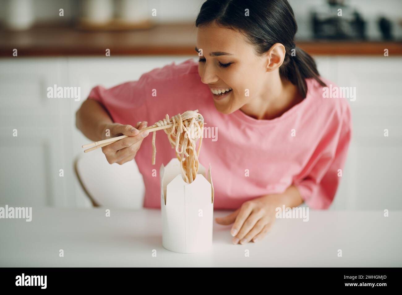 Happy smiling girl sitting in the kitchen. Cute young woman in casual ...