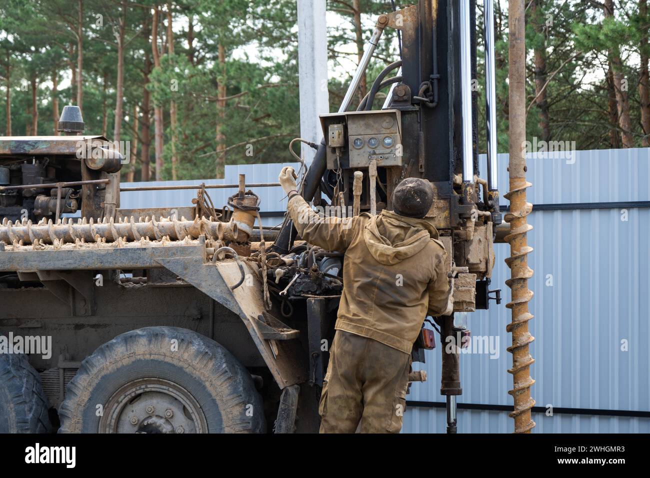 Team of workers with drilling rig on car are drilling artesian well for ...