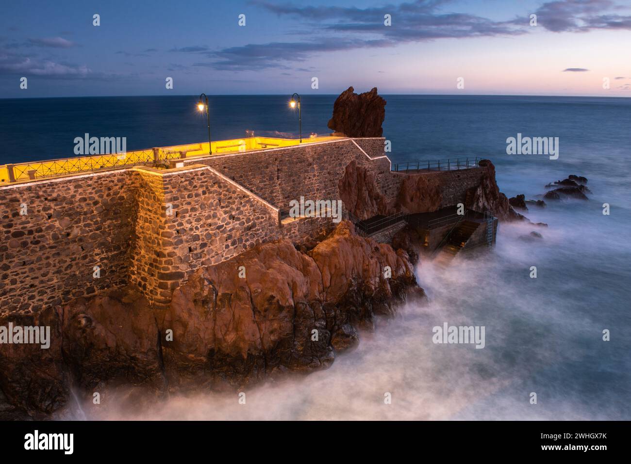 Rocks at Ponta do Sol, Madeira beach with promenade on cliffs. Sunset ...