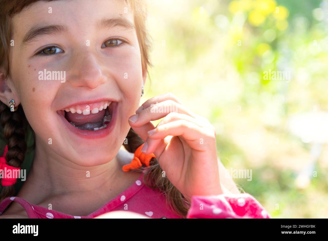 Toothless happy smile of a girl with a fallen lower milk tooth close-up. Changing teeth to ...