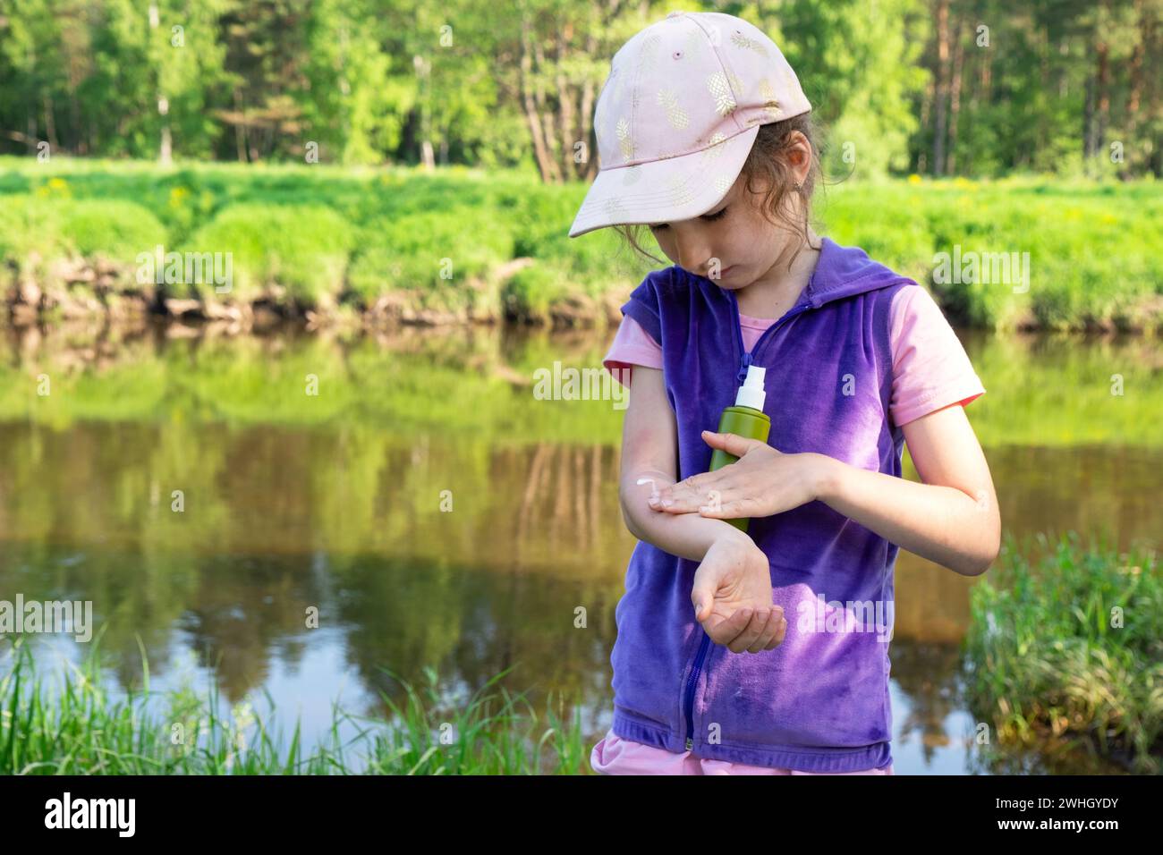 Girl sprays mosquito spray on the skin in nature that bite her hands ...