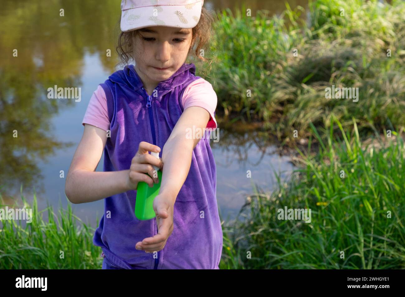 Girl sprays mosquito spray on the skin in nature that bite her hands ...