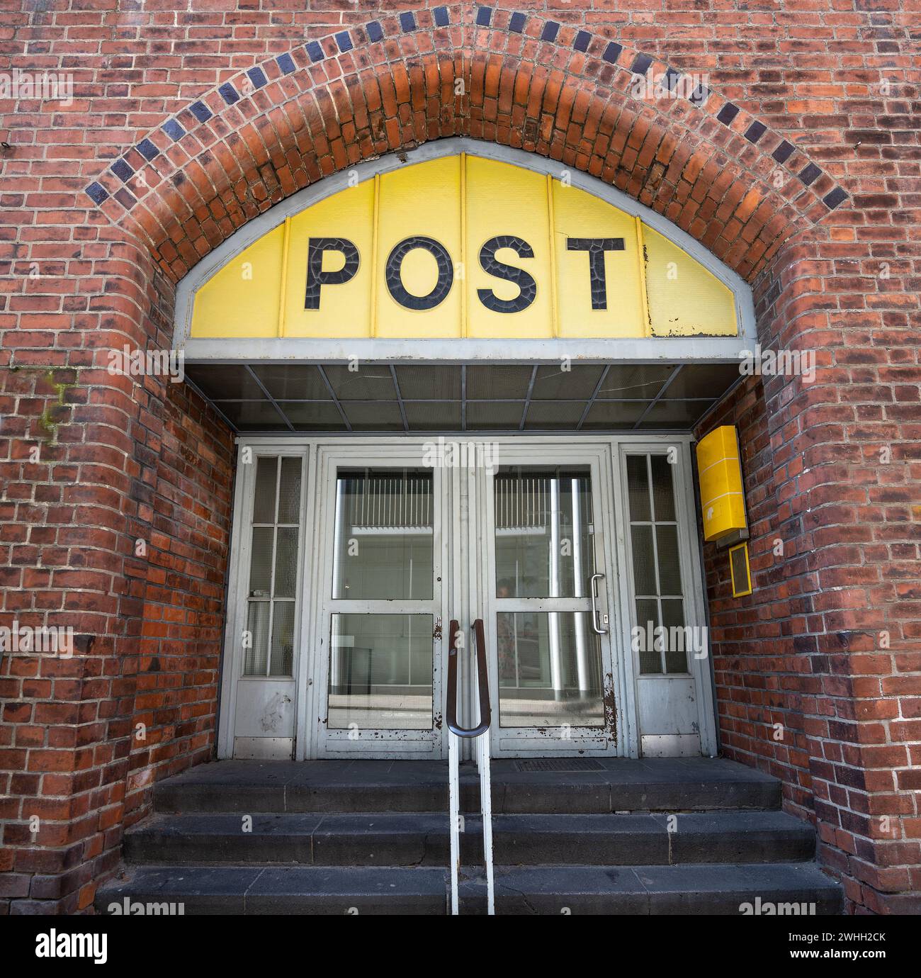 Entrance to the Post office in an historic building with a yellow sign ...