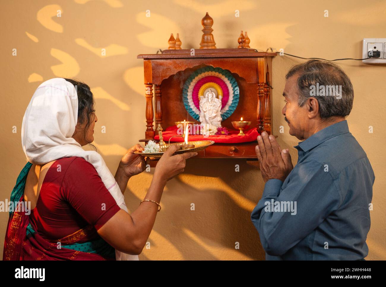 Devotional Indian woman giving aarthi to husband after offering to god ...