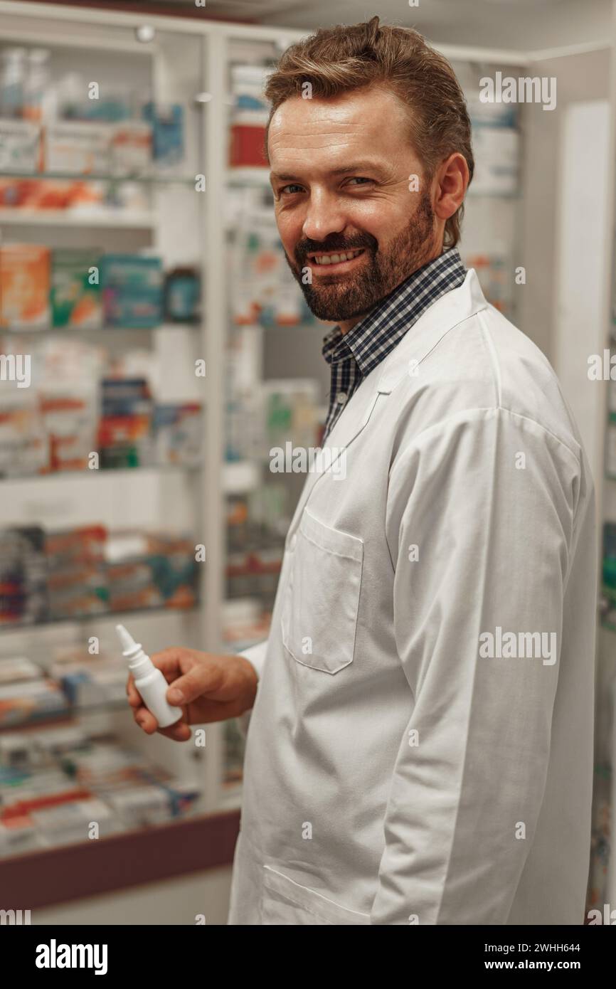 Male pharmacist and white coat holding nose spray while working at a ...
