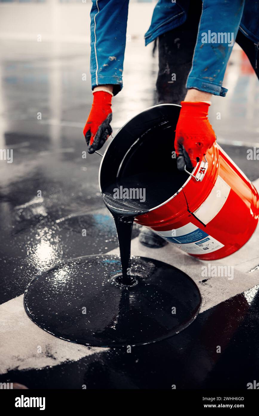 Man pours epoxy resin from a bucket to the new floor for coating Stock ...