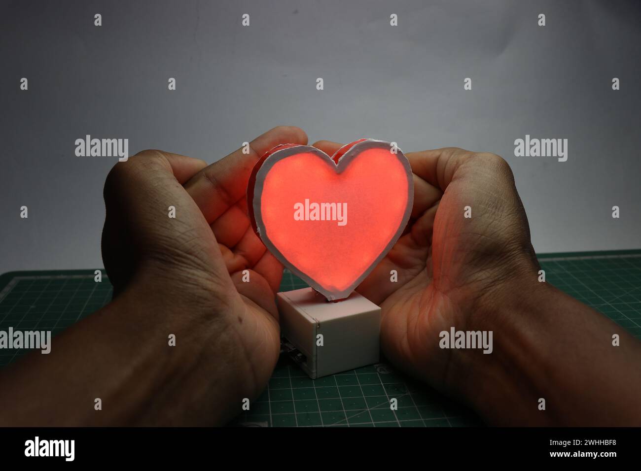 LED heart made using 3D print technology being covered with hands ...