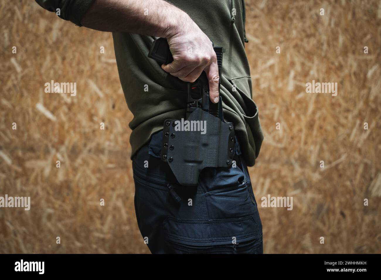 The man takes out a tactical pistol from his holster, close-up photo ...