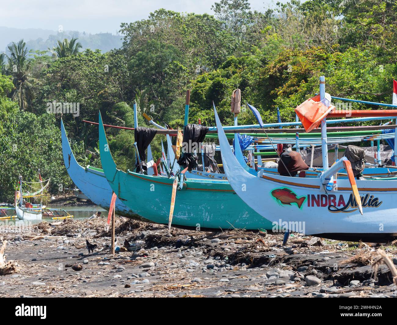 Traditional Indonesian fishing boat with outriggers on a stony beach in ...