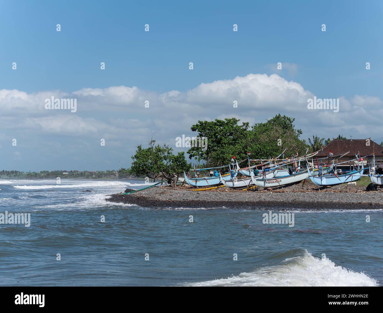 Traditional Indonesian fishing boat with outriggers on a stony beach in ...