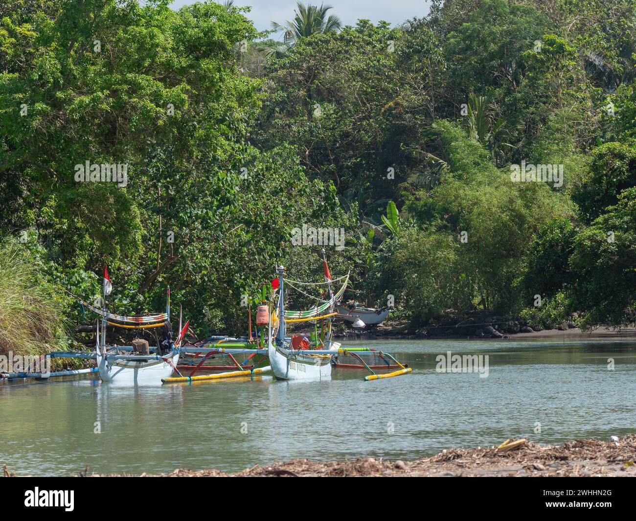 Traditional Indonesian fishing boat with outriggers on a river in ...