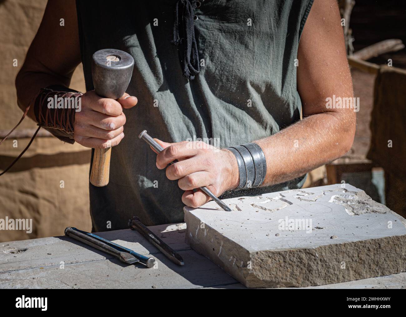 stonemason working with his tools, focused in the foreground with ...