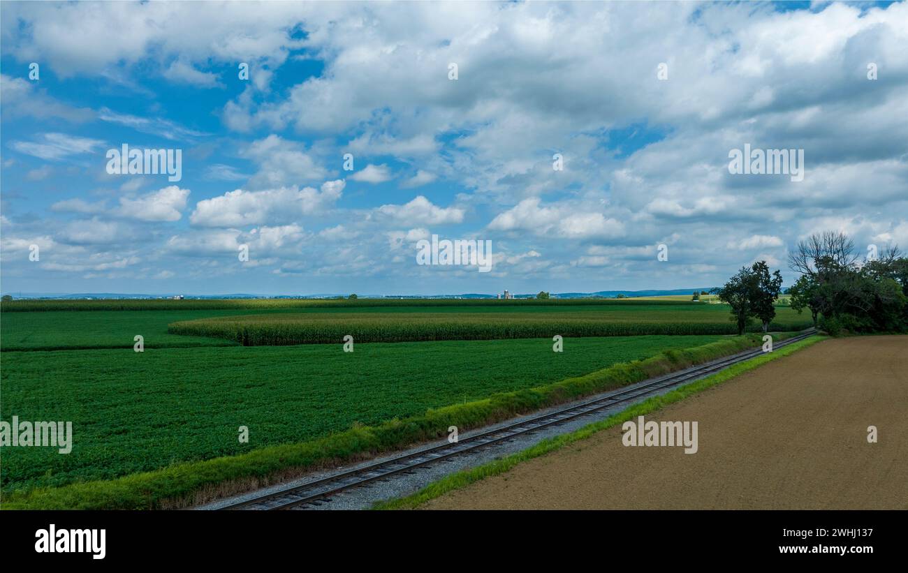 Railroad Tracks Curve Gently Through A Lush Agricultural Landscape With Fields Of Various Shades ...