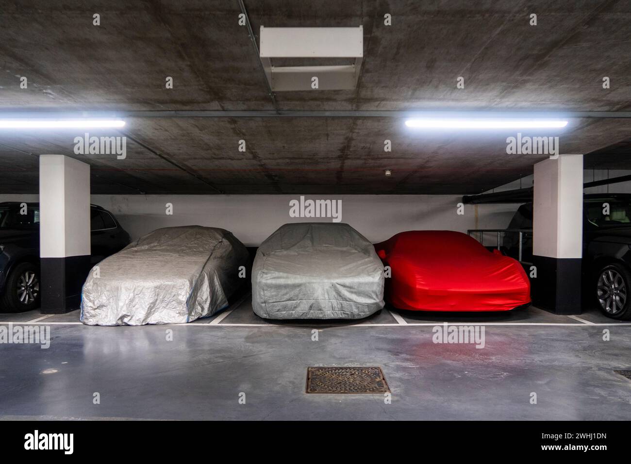 Three luxury cars under covers in a private garage Stock Photo - Alamy