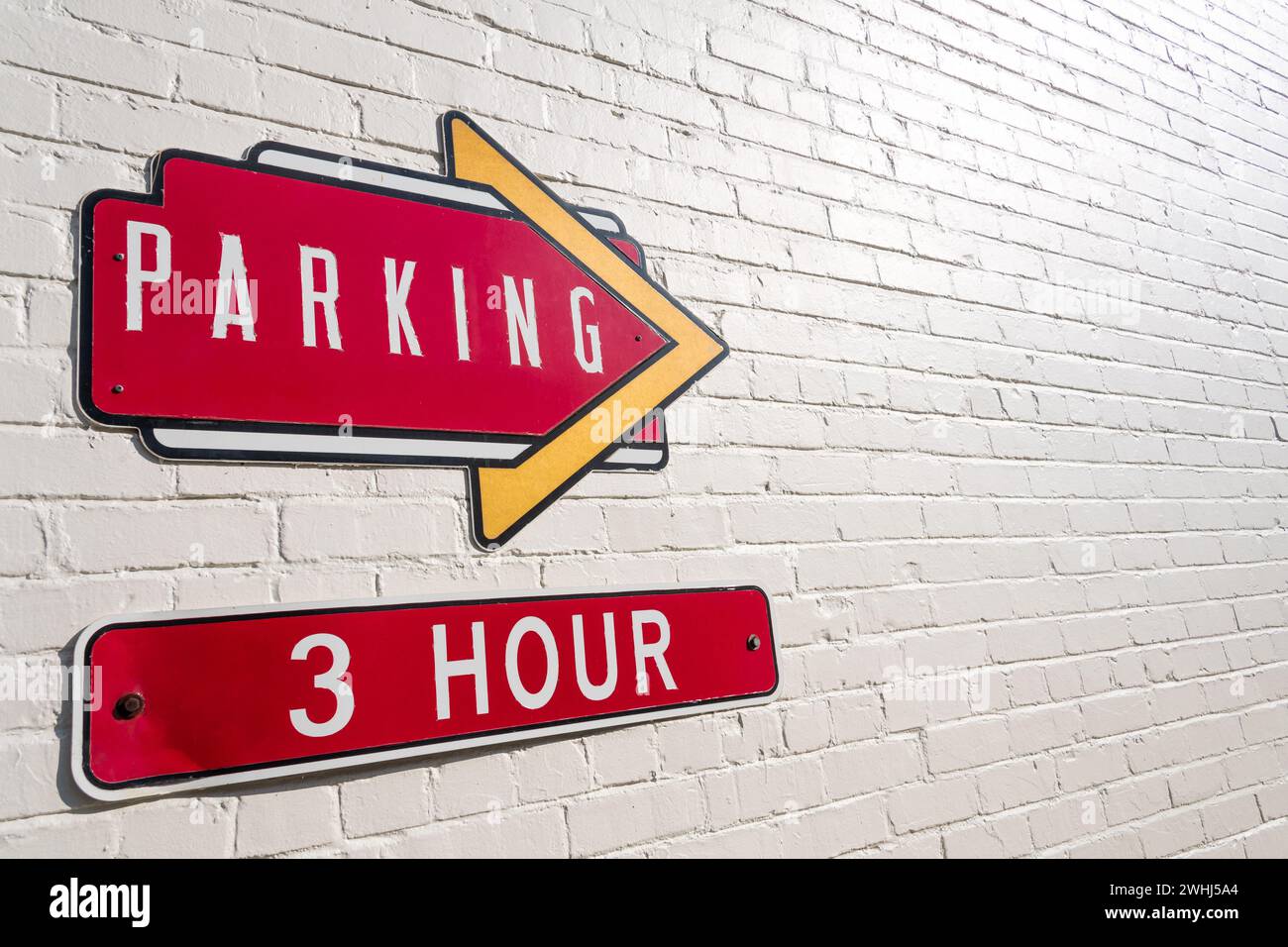 Bright red and yellow 3-Hour parking signs on white-painted brick wall ...