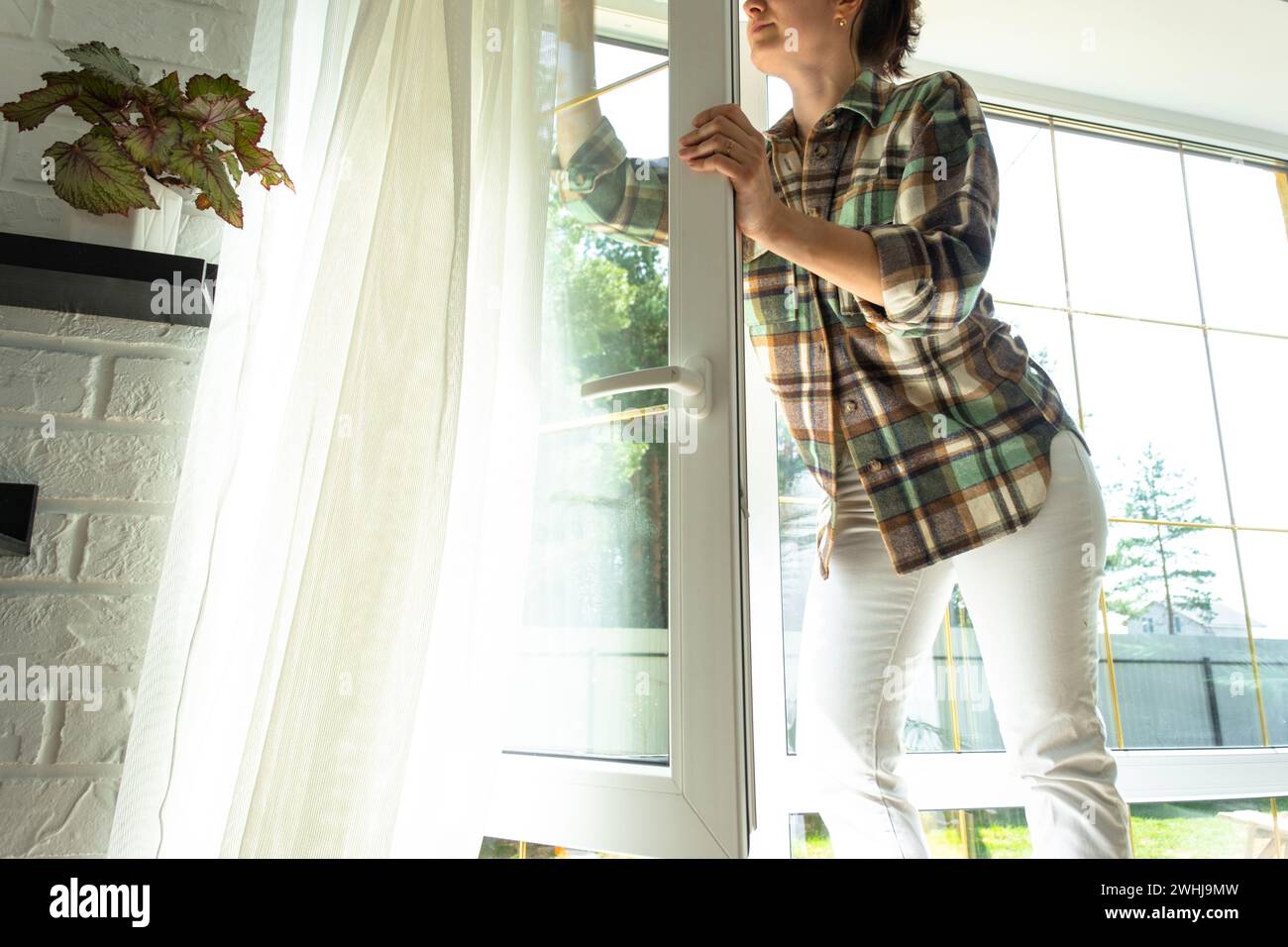 Woman manually washes the window of the house with a rag with spray ...