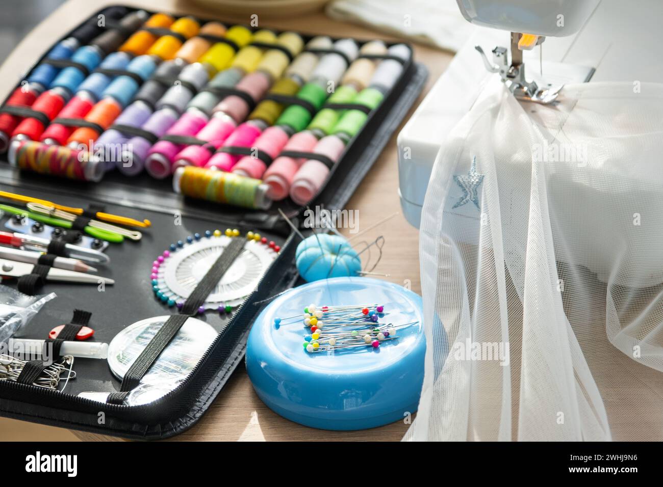 Sewing layout with multicolored spools of thread close-up, needles ...