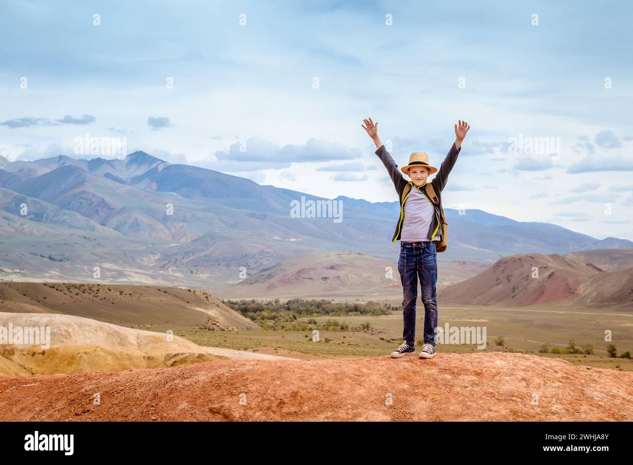 Happy boy traveler with his hands up on blue mountains background Stock ...