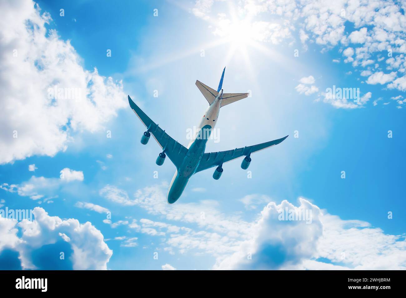 Airplane in the blue sky with clouds from below, high flying passenger ...