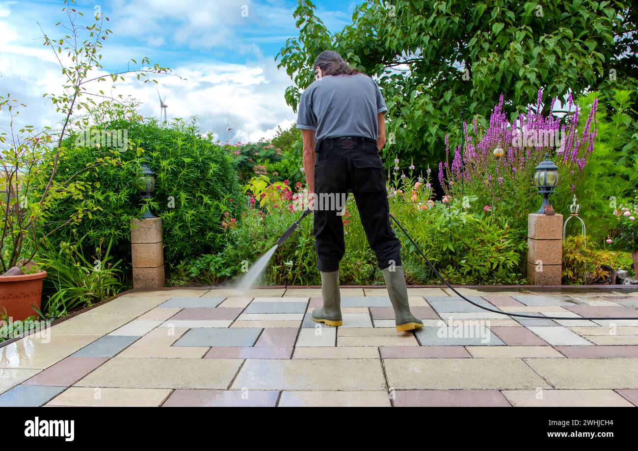 Cleaning stone slabs on patio with the high-pressure cleaner. Person ...