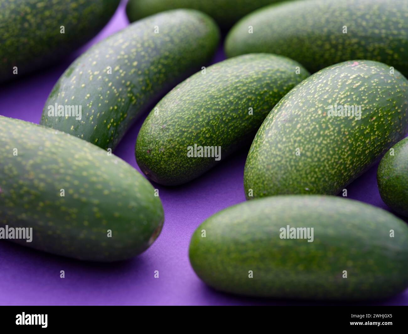 A close-ip shot of cocktail avocados or mini avocados on a purple ...