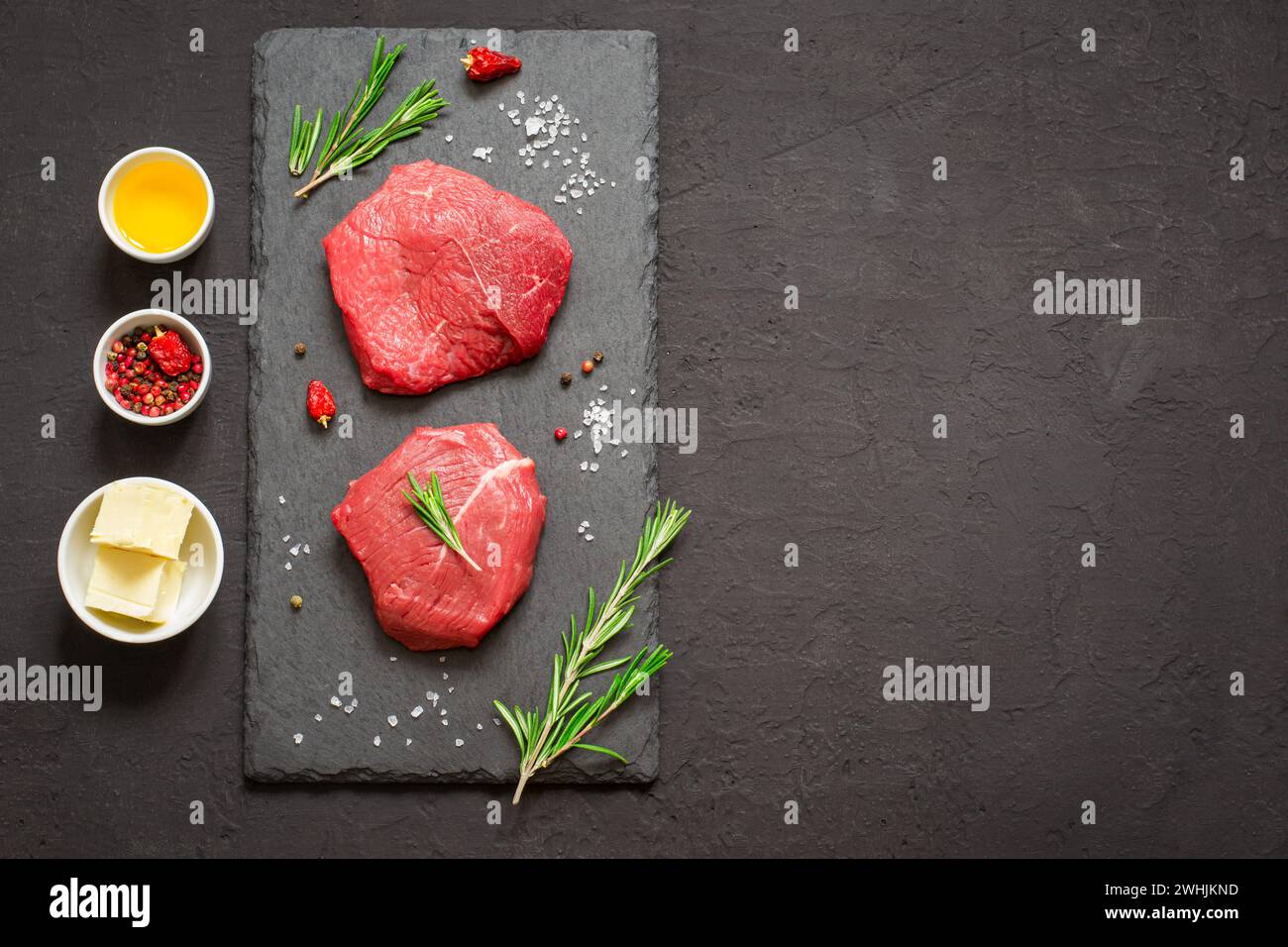 Raw meat beef steaks on black slate board, spices and ingredient Stock ...