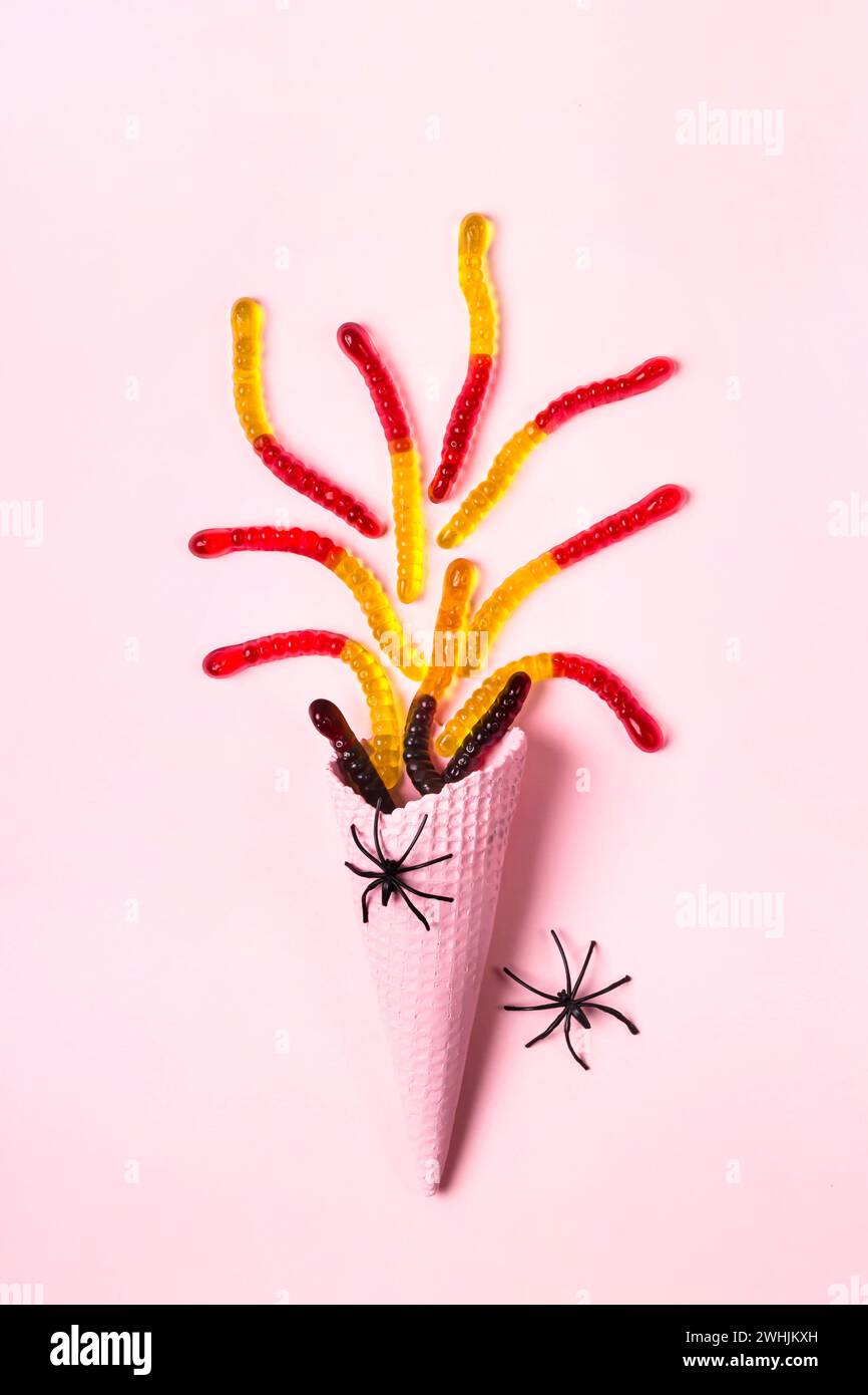 Pink ice cream cone with colorful marmalade worms and spiders. Minimal ...